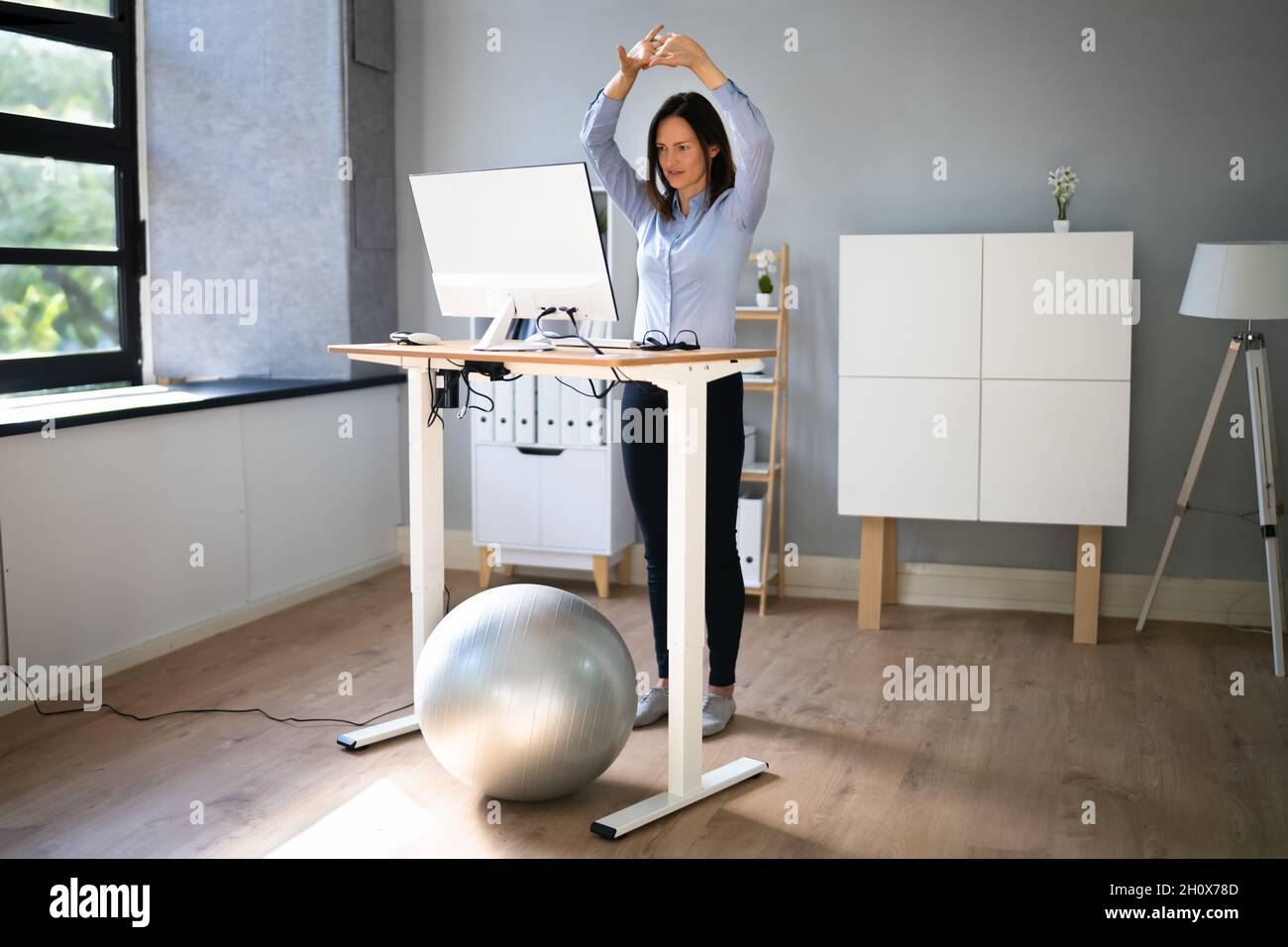 Worker Stretch Exercise At Stand Desk In Office Stock Photo - Alamy
