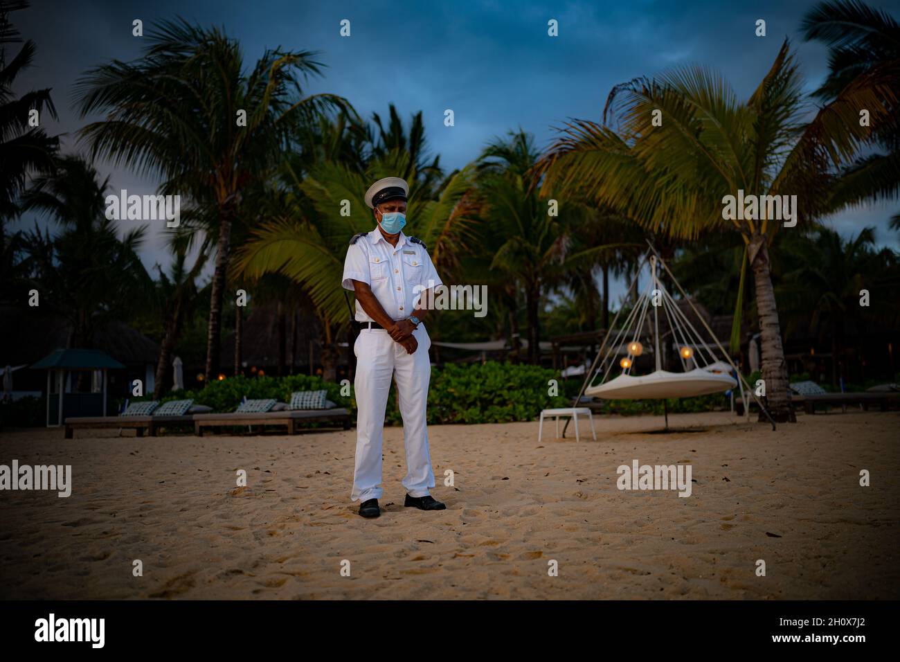 A security guard wears a medical facemask as he patrols a beach in ...