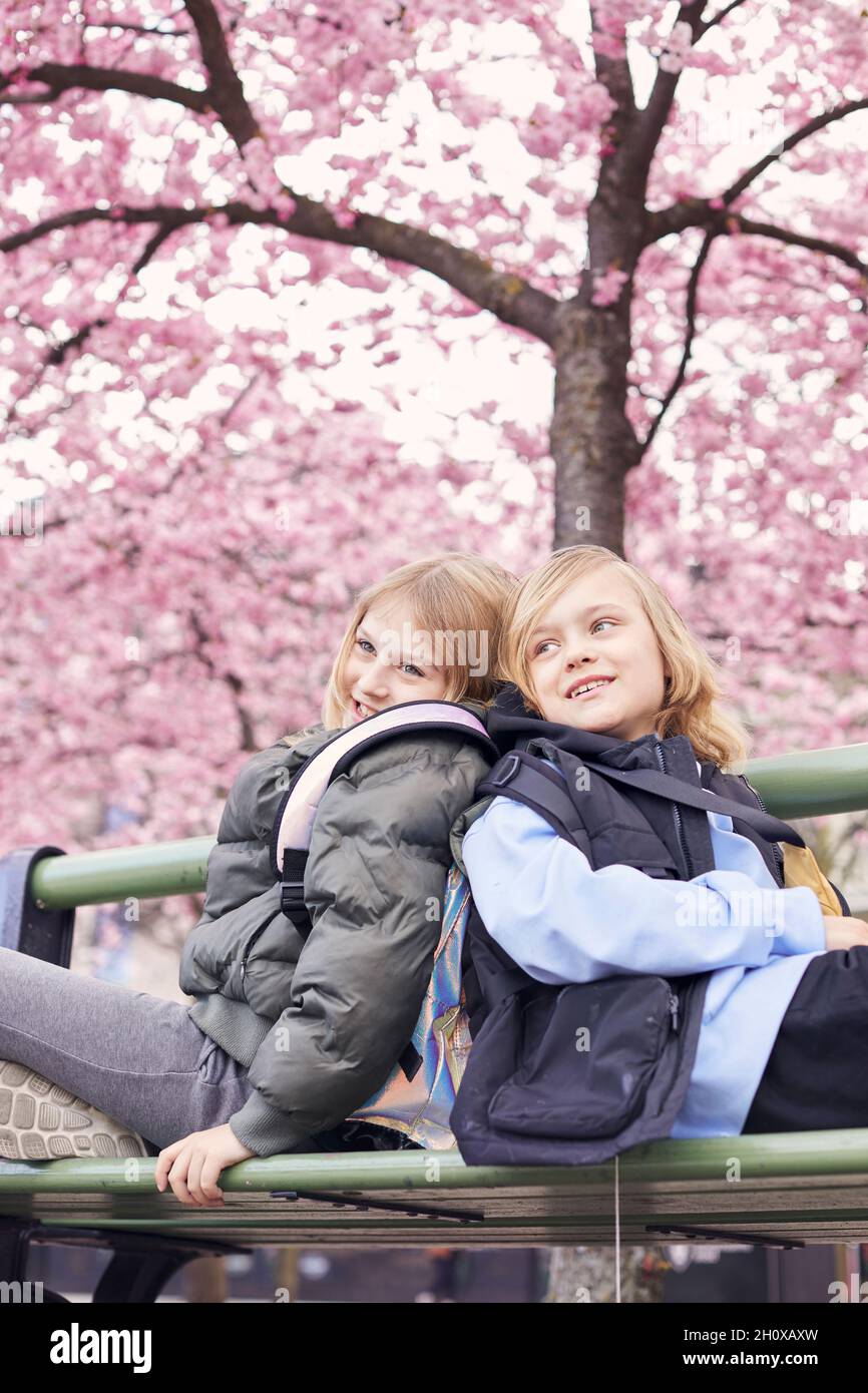 Girls sitting on bench Stock Photo - Alamy
