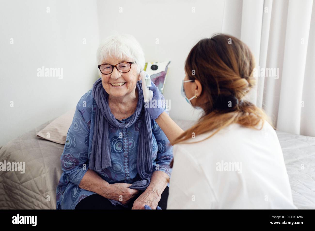 Nurse checking woman's temperature at home Stock Photo - Alamy