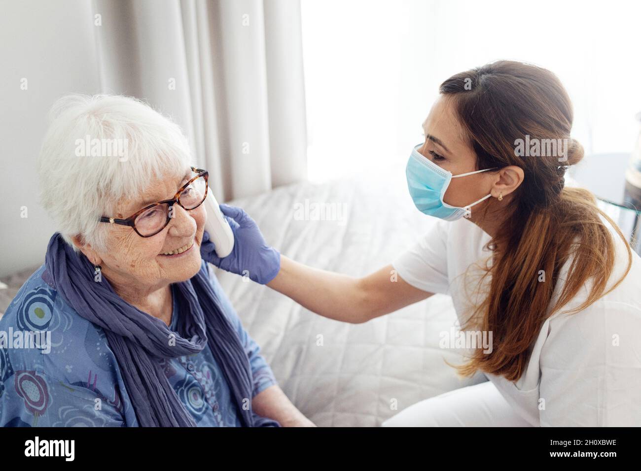Nurse checking woman's temperature at home Stock Photo - Alamy