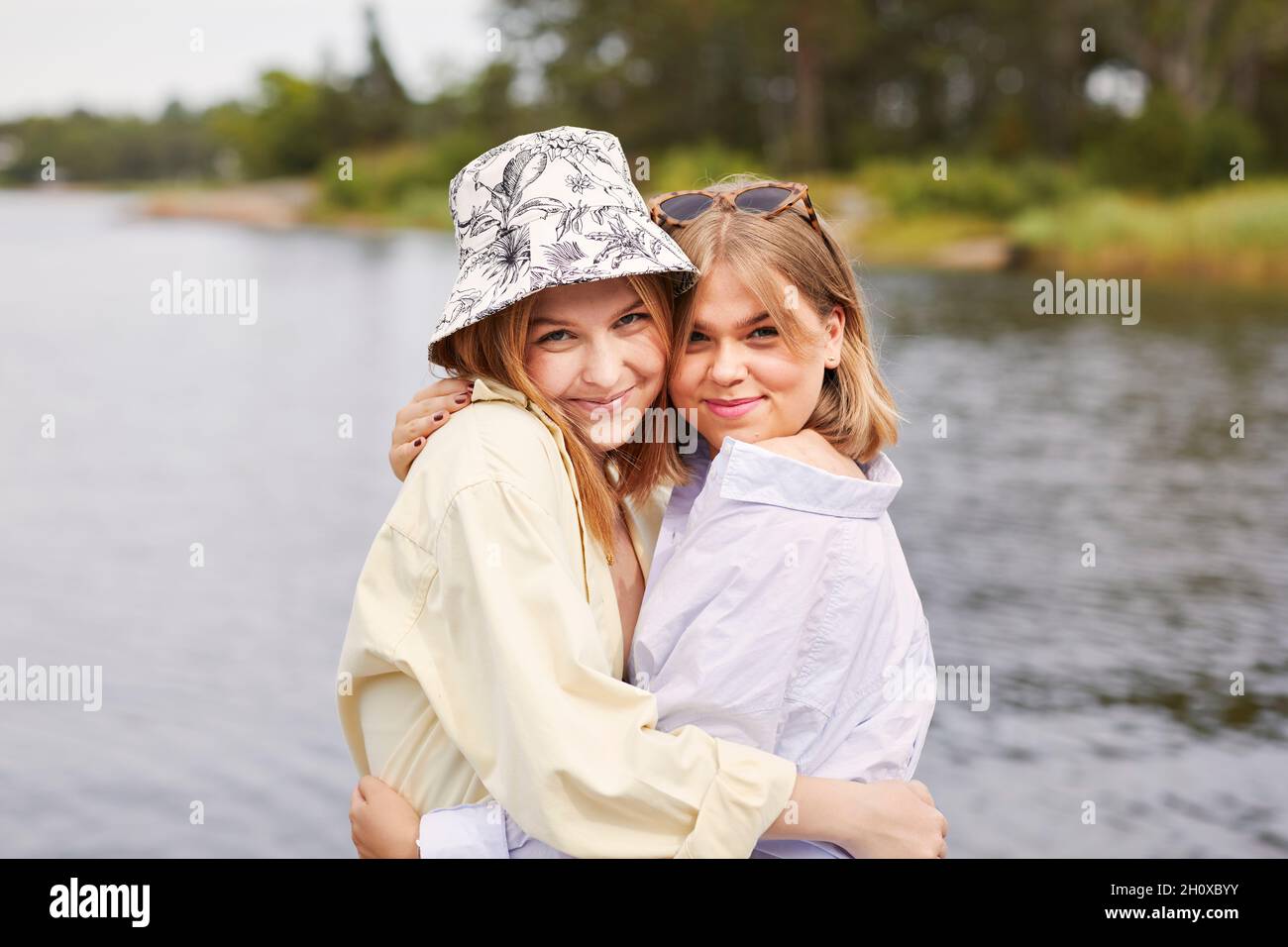 Two friends embracing at lakeside Stock Photo - Alamy