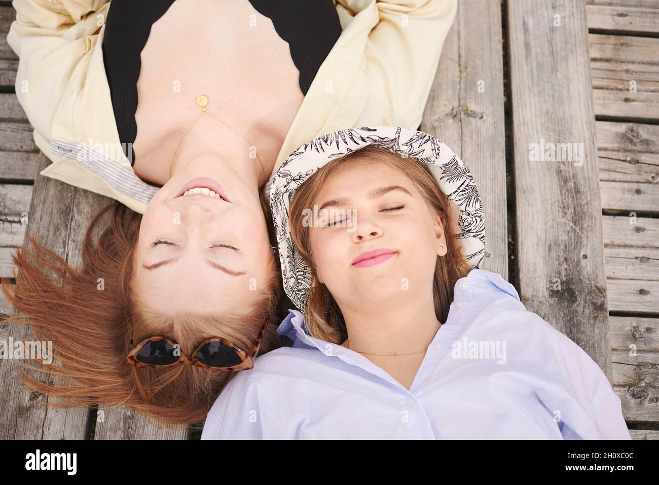 Two friends lying on pier Stock Photo - Alamy