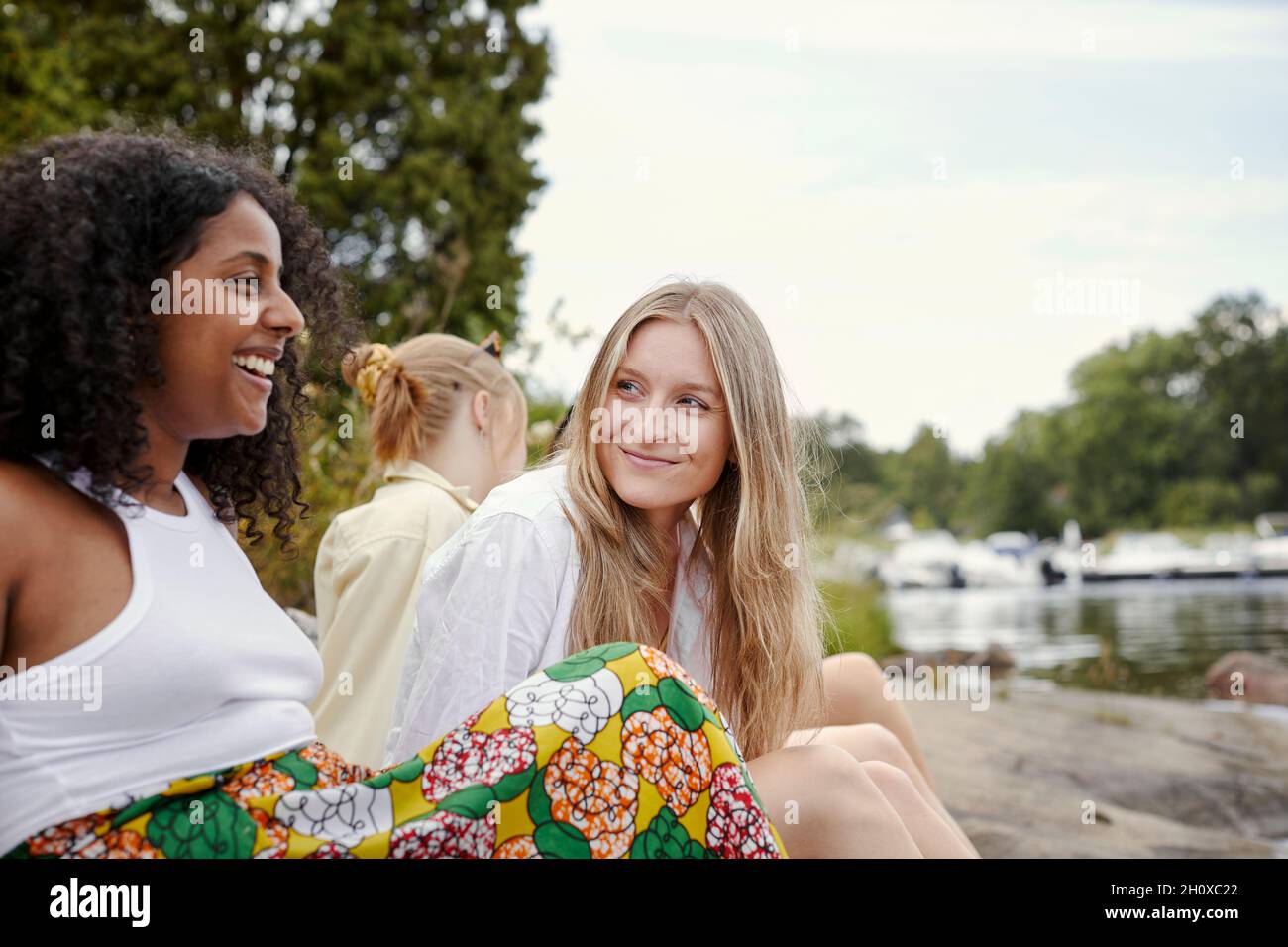 Group of friends resting at lakeside Stock Photo - Alamy