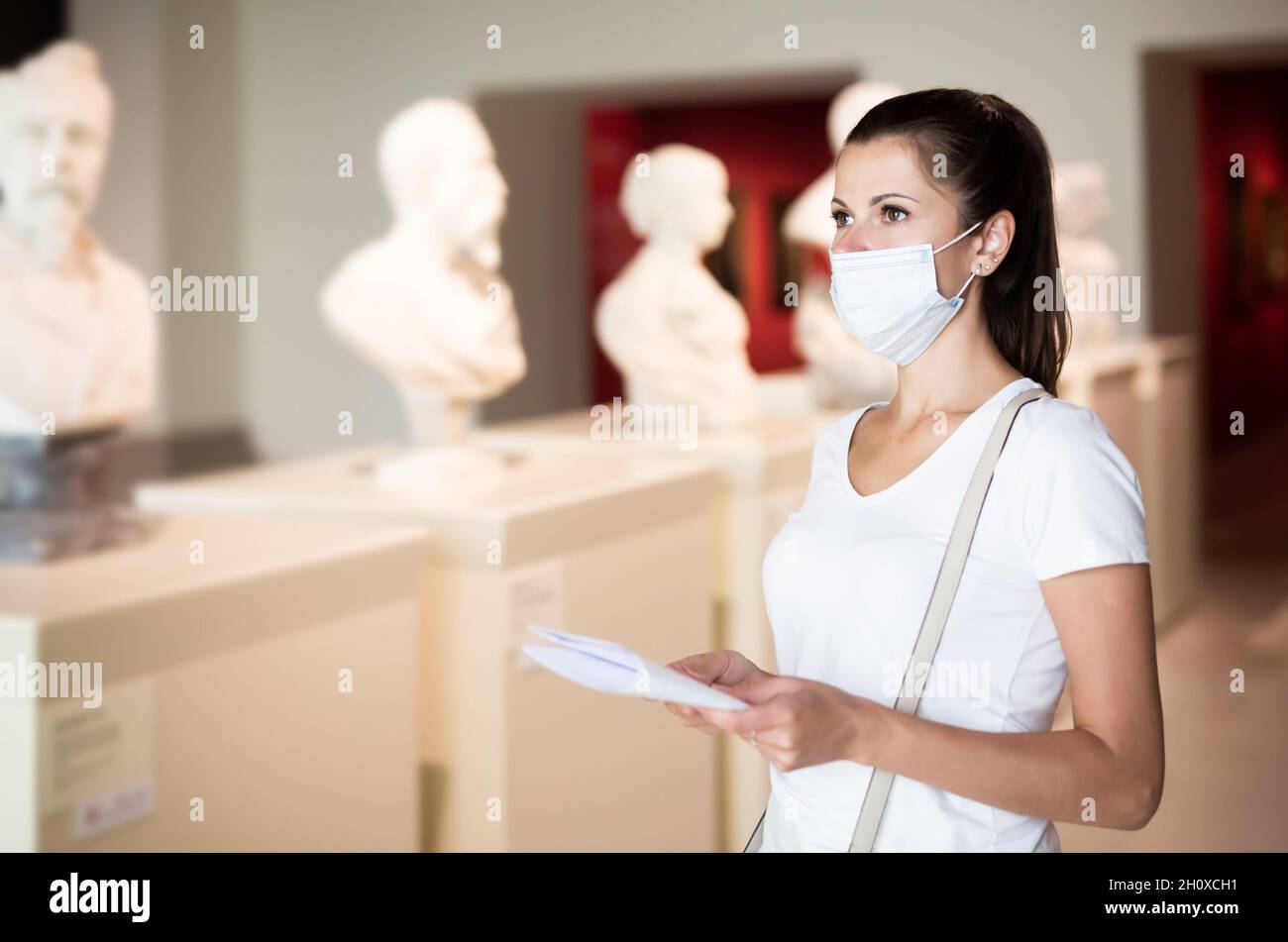 Woman in mask exploring sculptures in gallery Stock Photo - Alamy