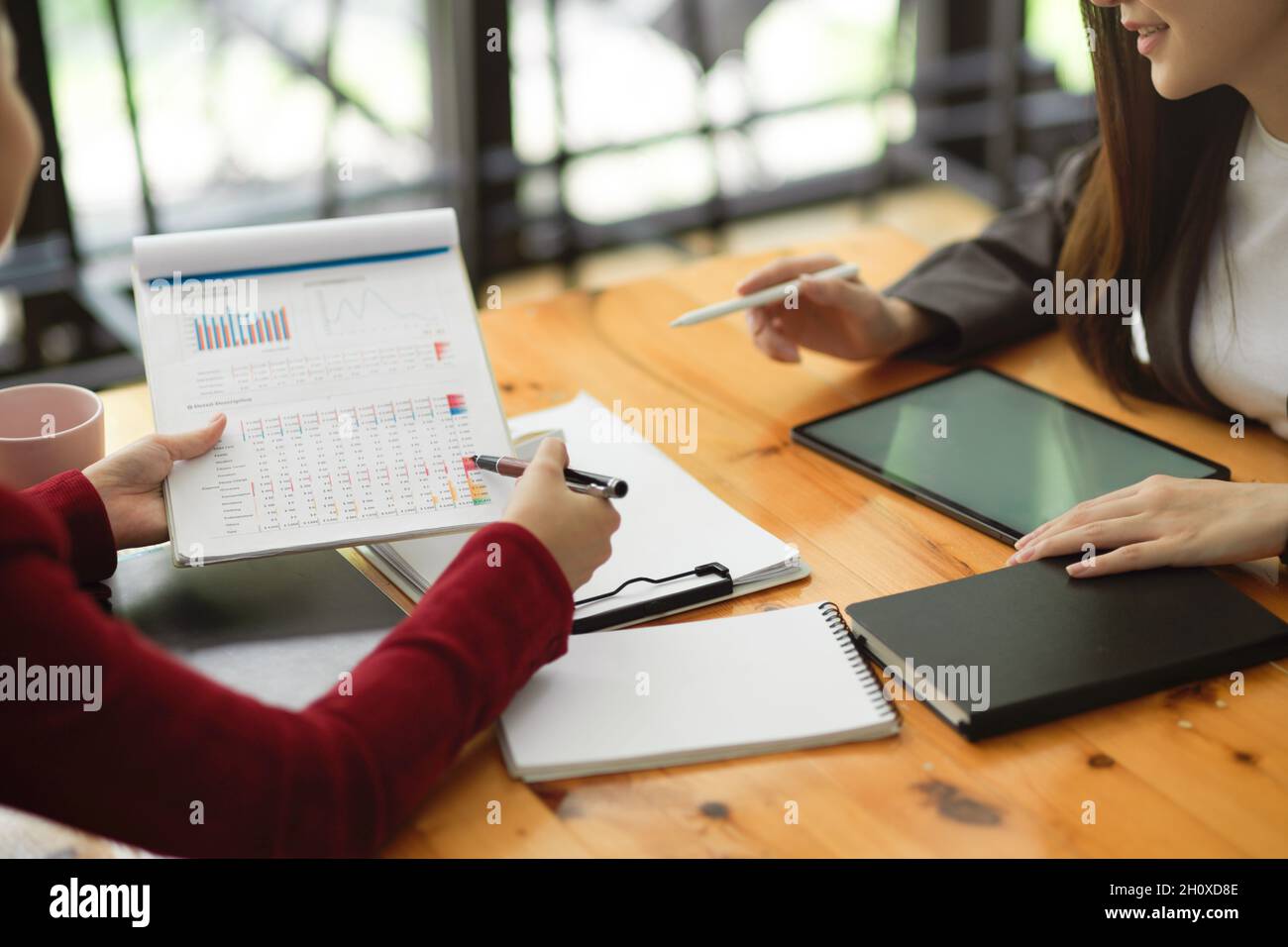 Two of businesswomen colleagues looking at business data spreadsheet in ...