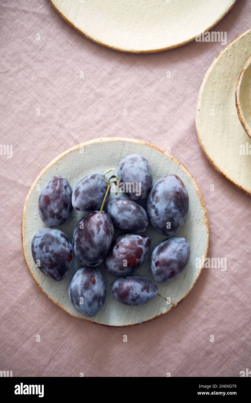 Fresh juicy sweet plums on an unusual clay plate Stock Photo - Alamy