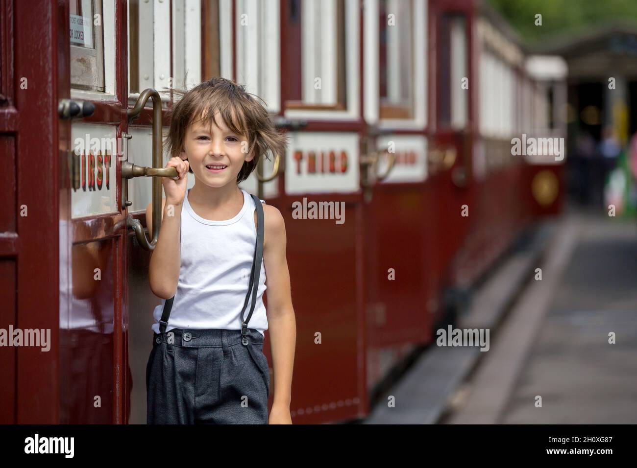 Beautiful child, dressed in vintage clothes, enjoying old steam train ...