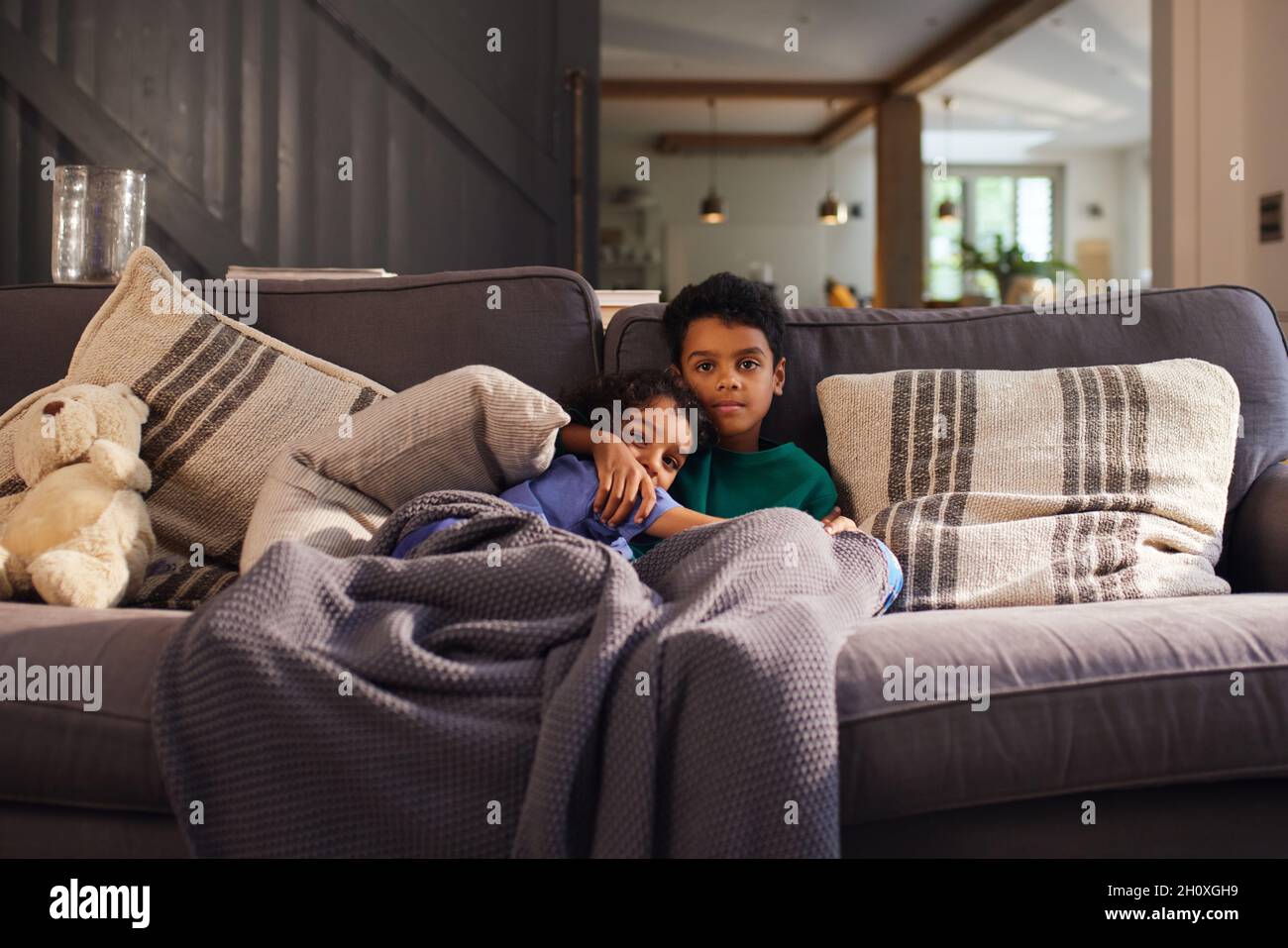 Two boys cuddling on sofa under blanket Stock Photo - Alamy