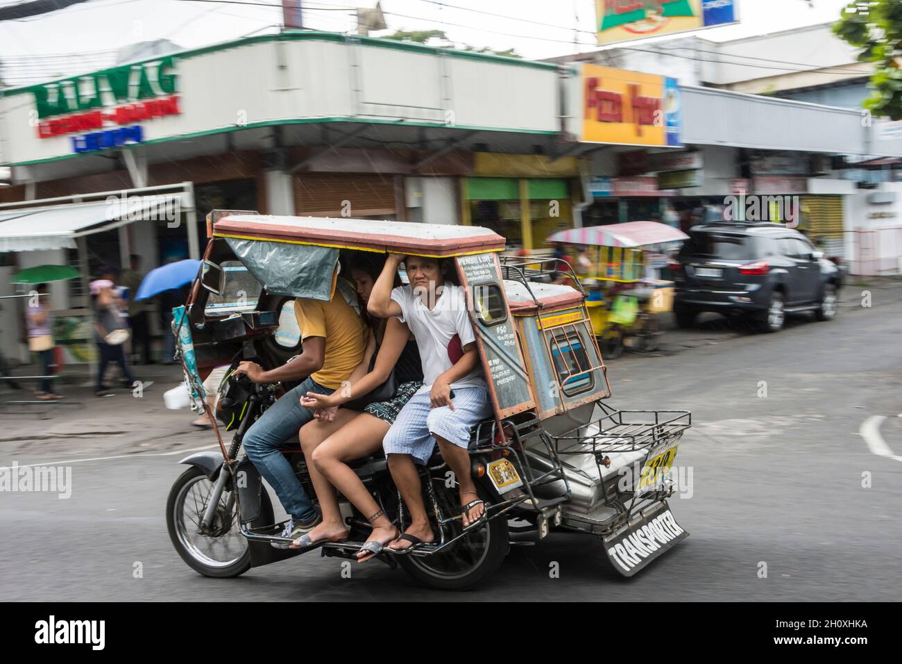 Typical Filipino motor taxi with passengers in the streets of Naga city ...