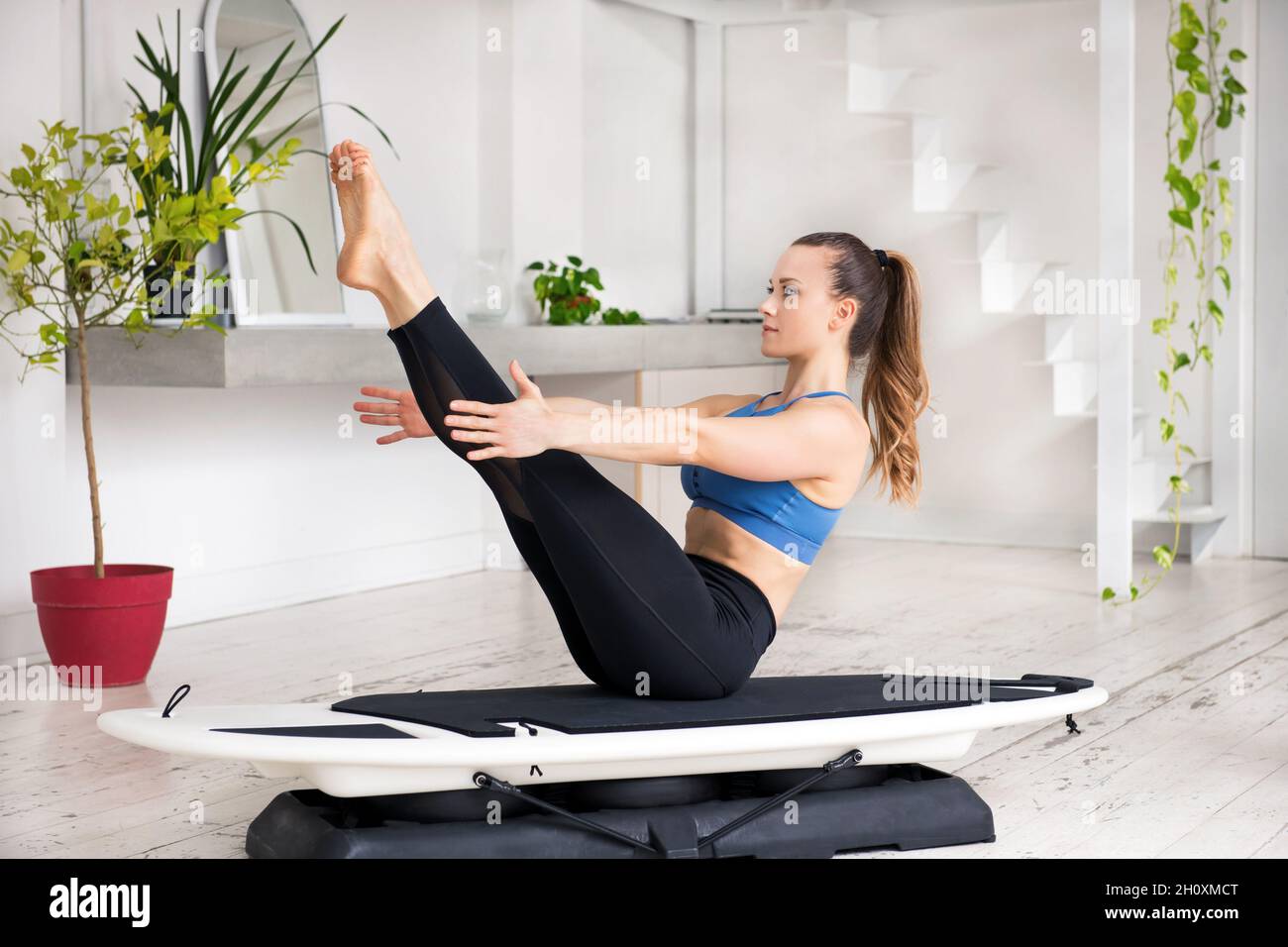 Young woman athlete performing a Navasana or yoga Boat Pose on a ...