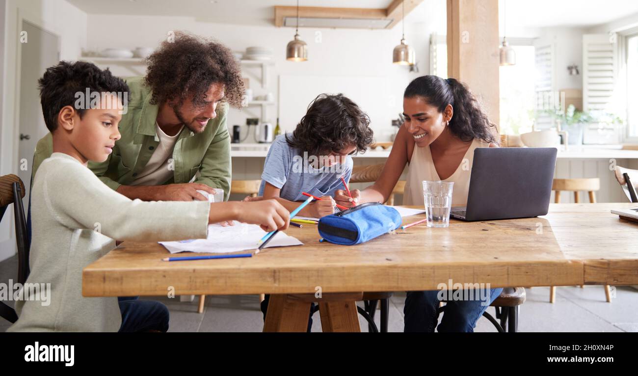 Boys doing homework with parents working from home Stock Photo - Alamy