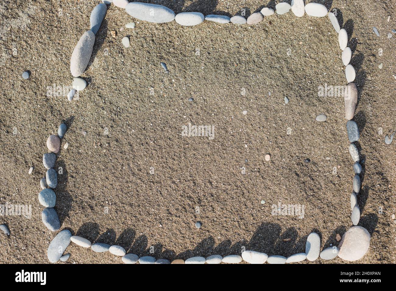Rectangular horizontal frame made of beach pebbles on the sand ...