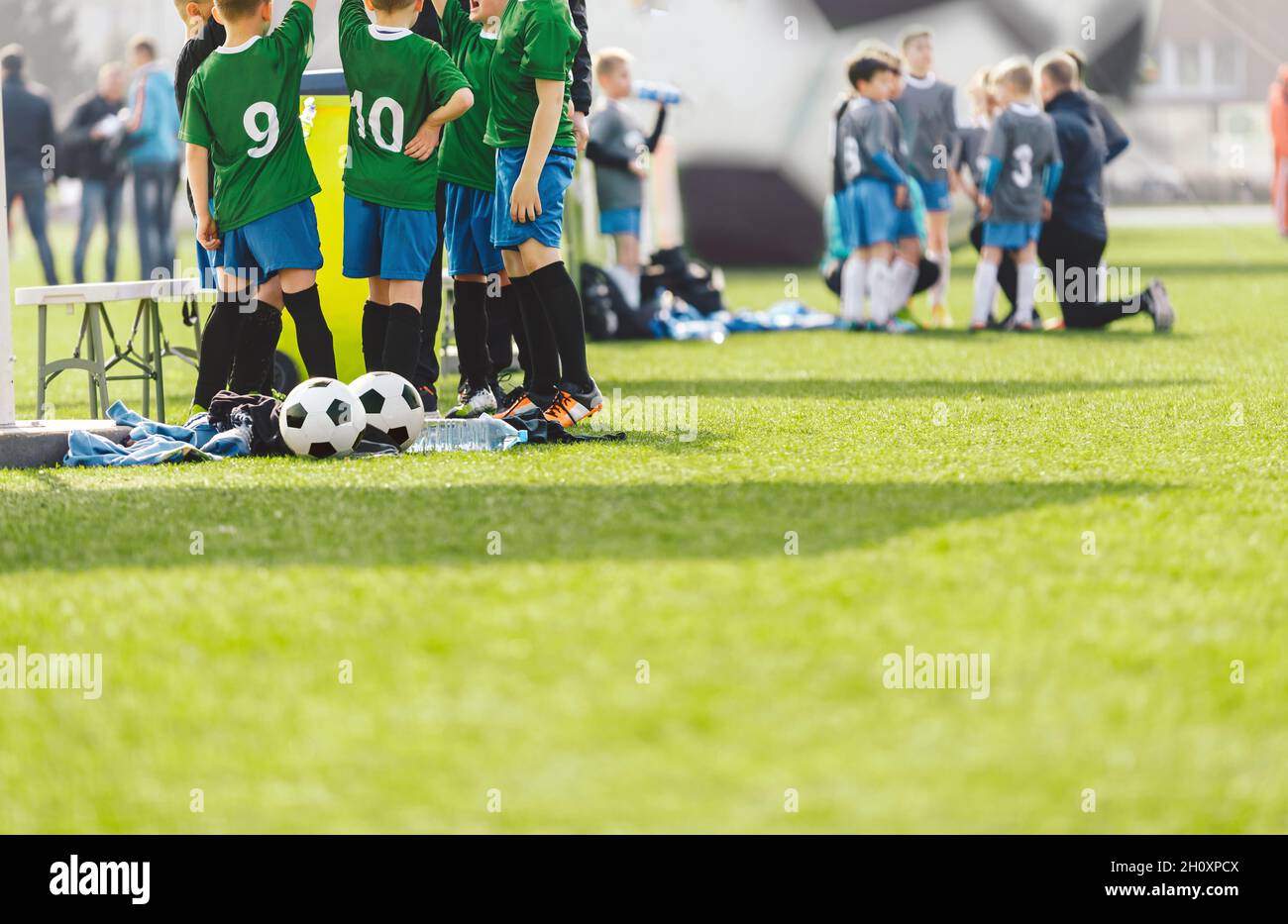 Children in two soccer teams standing in groups with young school ...