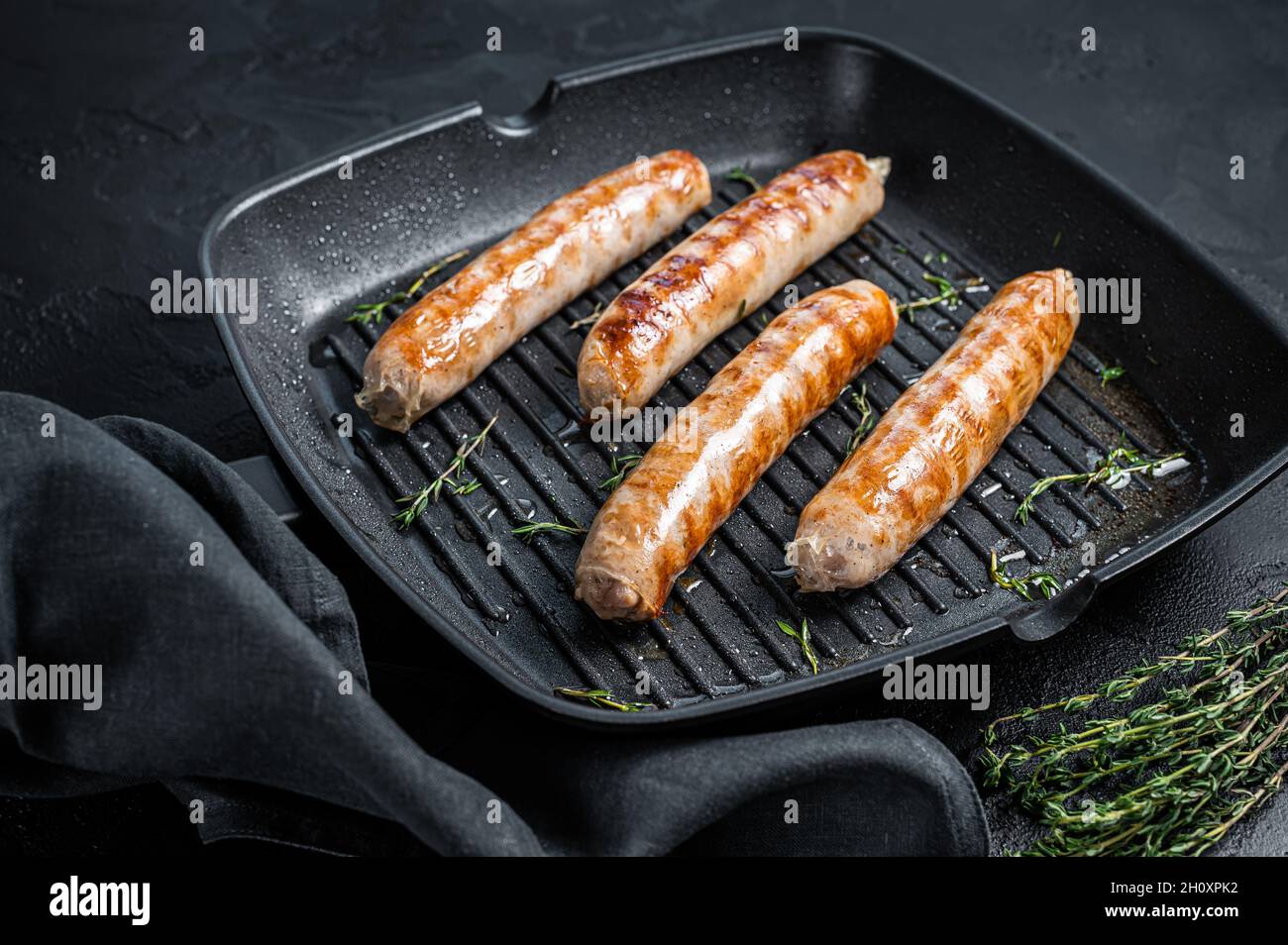 German grilled Bratwurst sausages in a grill pan. Black background. Top ...