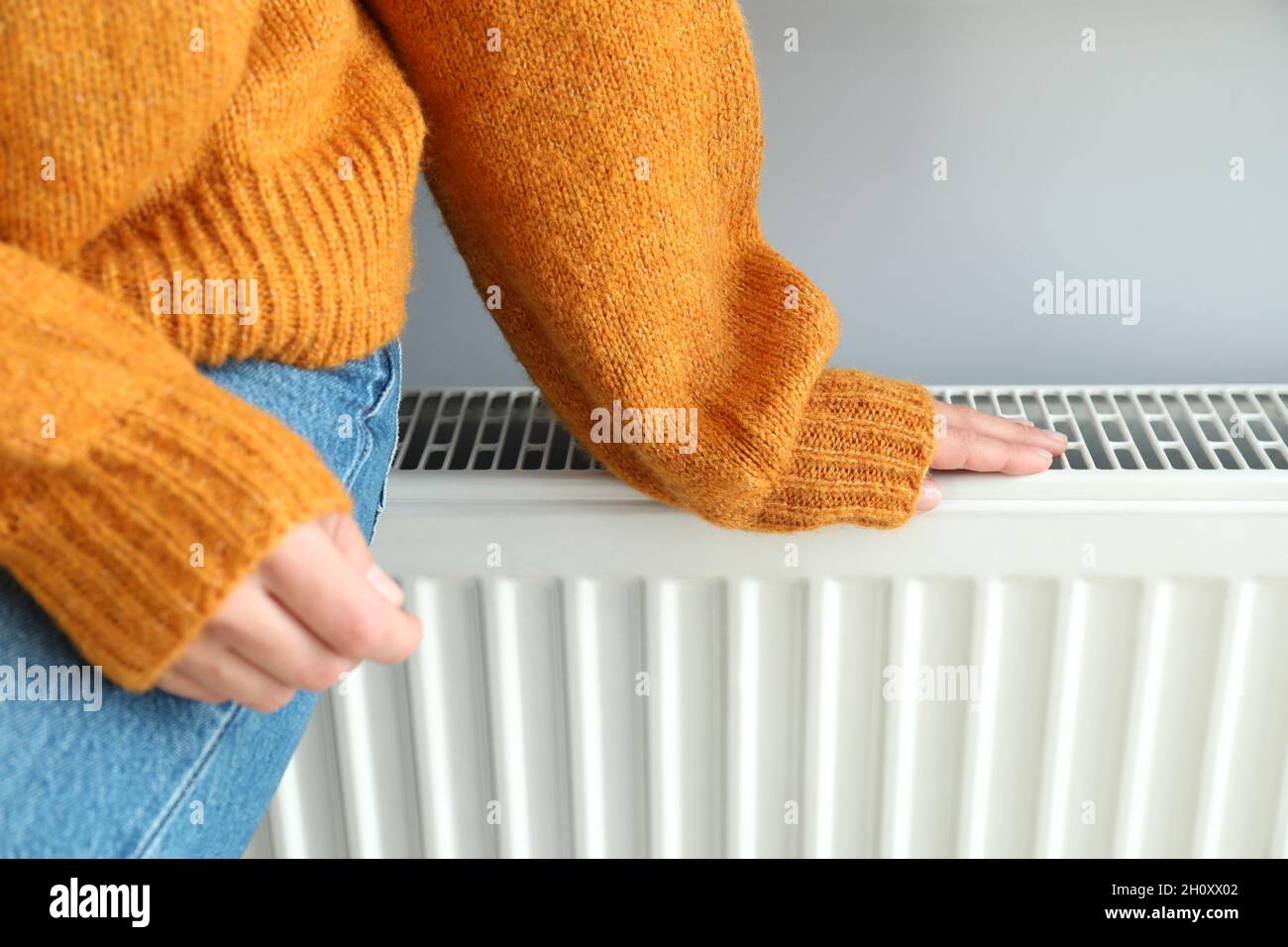Concept of heating season with girl sitting on radiator Stock Photo - Alamy