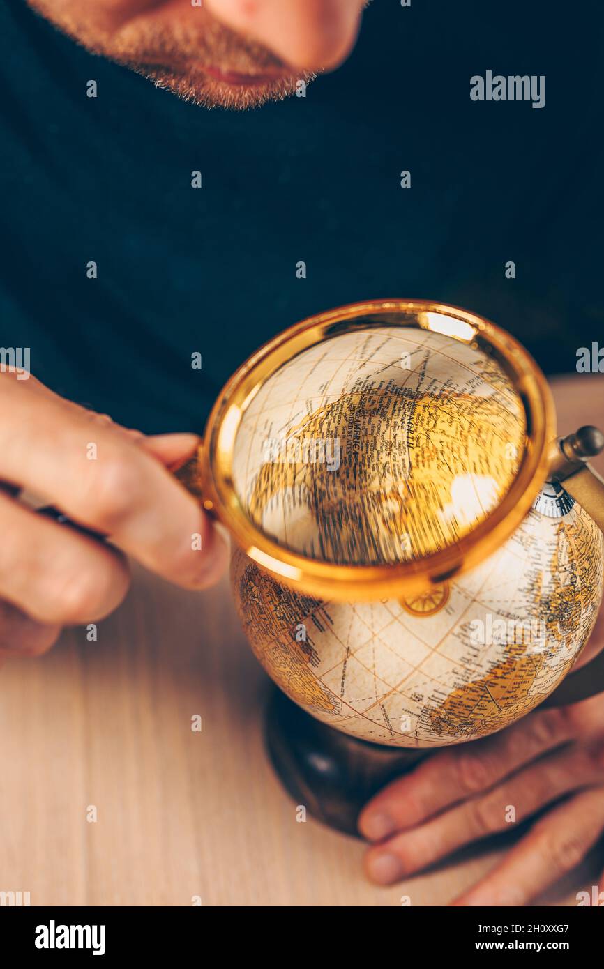 Male geographer examines a map of america - a magnifying glass in the ...