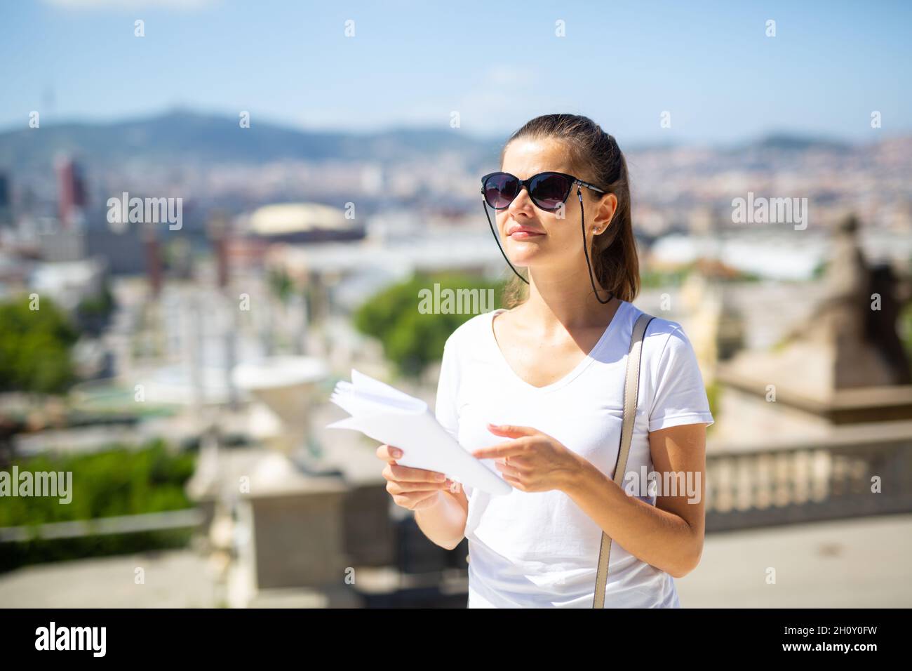 Young woman with paper guide observing sightseeings Stock Photo - Alamy