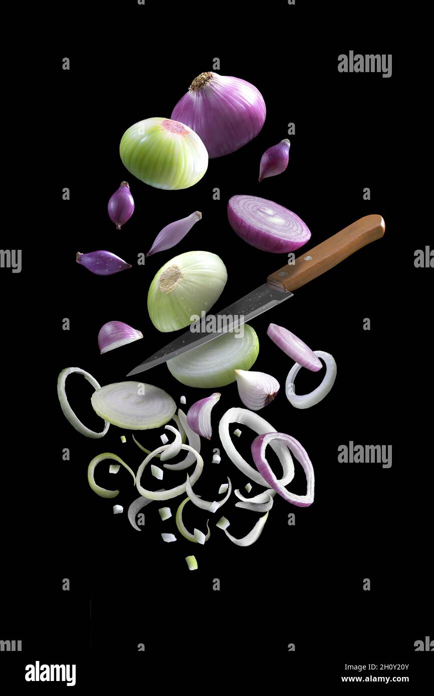 Vertical shot of sliced falling onion with a knife on black background ...