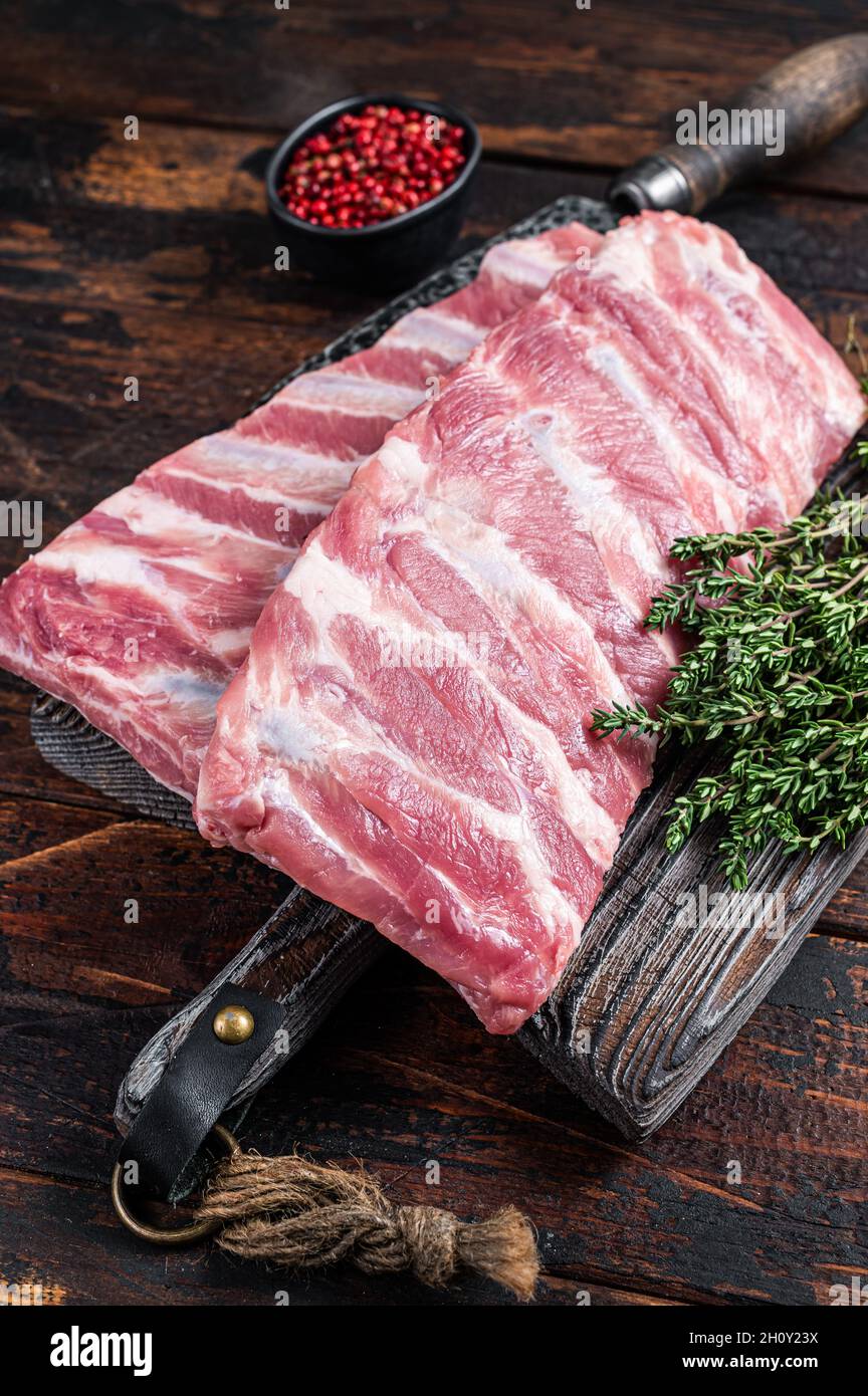 Rack of Fresh Raw pork spare ribs on butcher board. Dark wooden ...