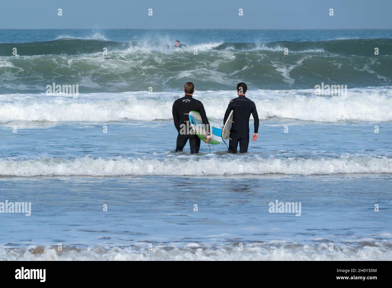 Two surfers head out into the waves on an October day at Putsborough ...