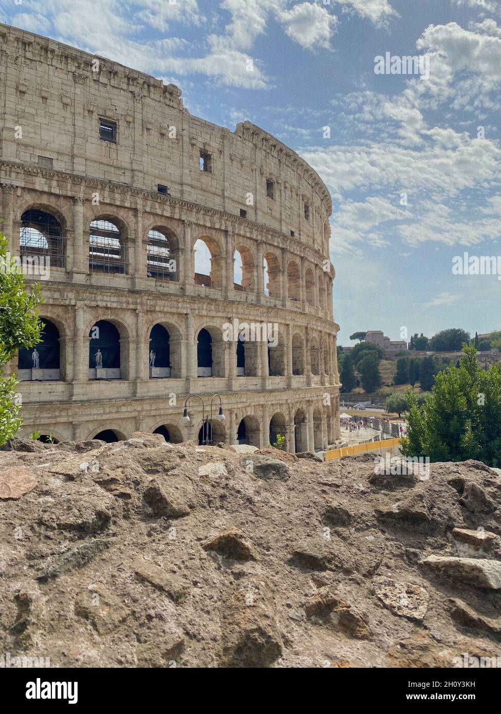 Vertical shot of the exterior of Colosseum under a blue sky with tiny ...
