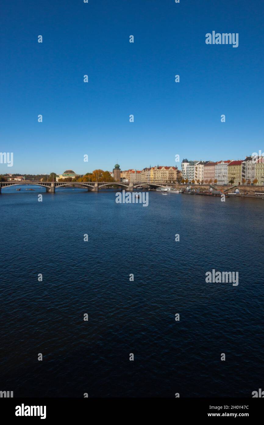 Vertical shot of the Vltava river, Moldau, a bridge, and the buildings ...
