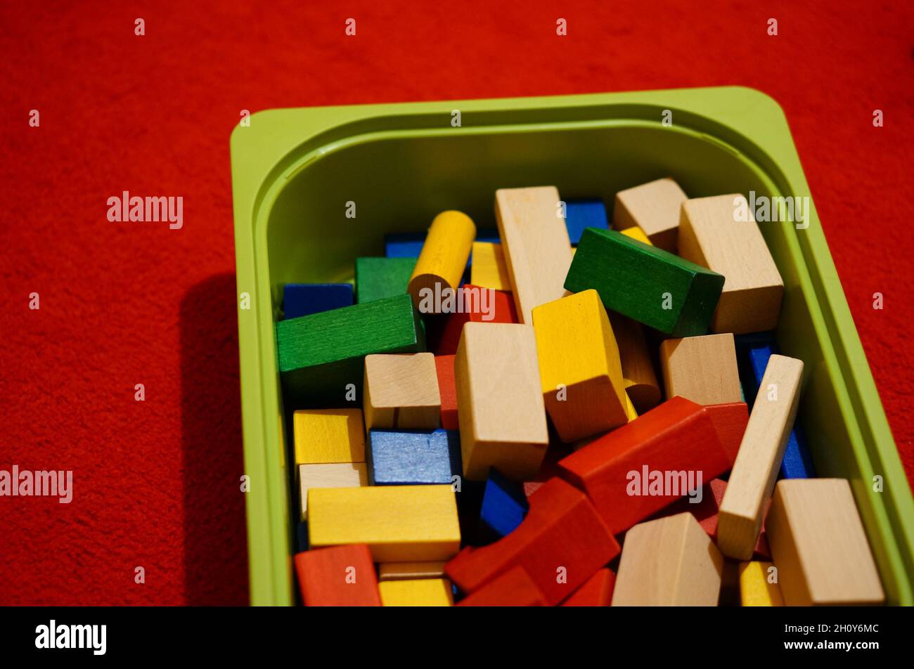 Green container with colorful wooden blocks for a toy constructor on a ...