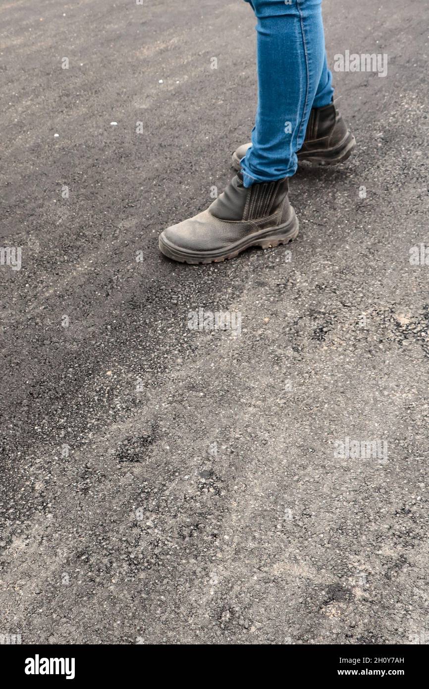 Foot of an unidentified person, wearing jeans and wearing a very worn ...