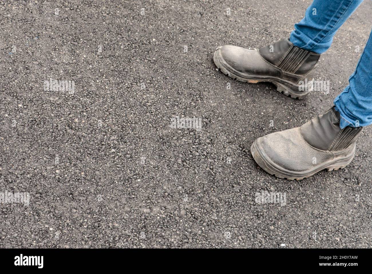 Foot of an unidentified person, wearing jeans and wearing a very worn ...