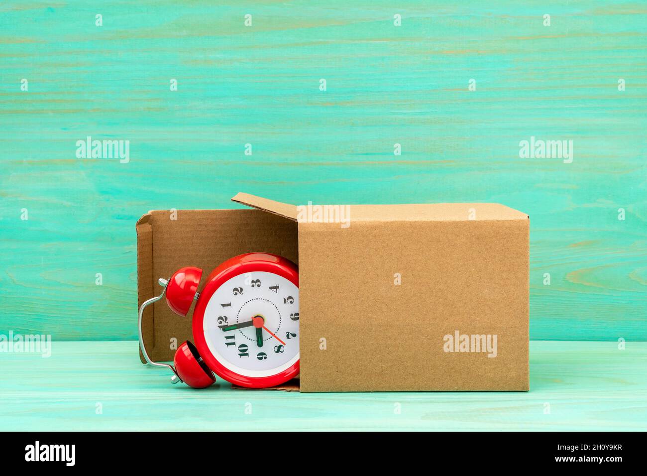 Alarm clock in a cardboard box on wooden background Stock Photo - Alamy