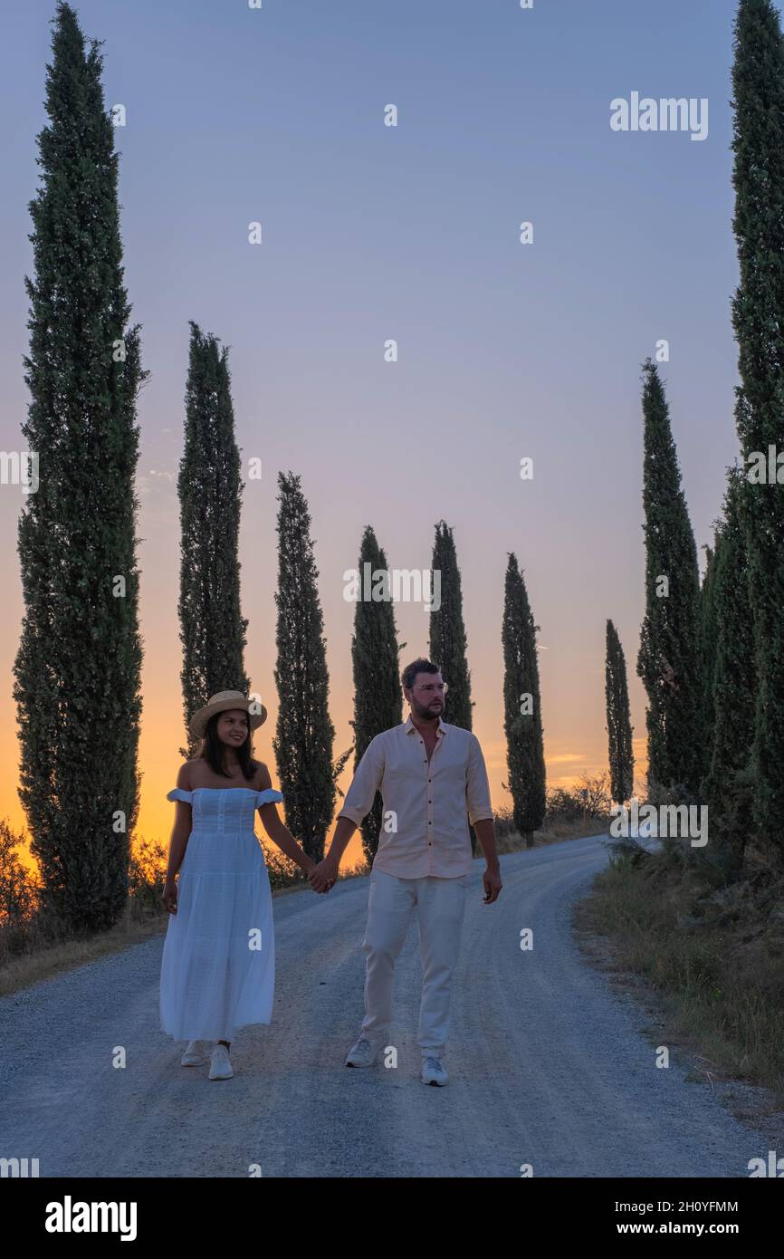 Tuscany landscape with grain fields, cypress trees, couple man and ...