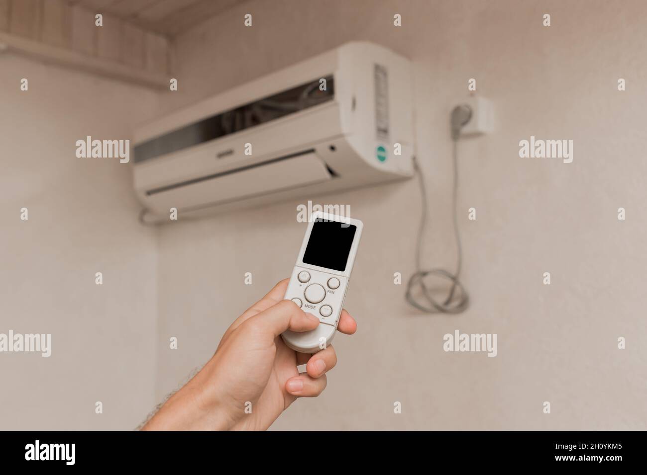 The guy's hand holds the remote control of the air conditioner. Cooling ...