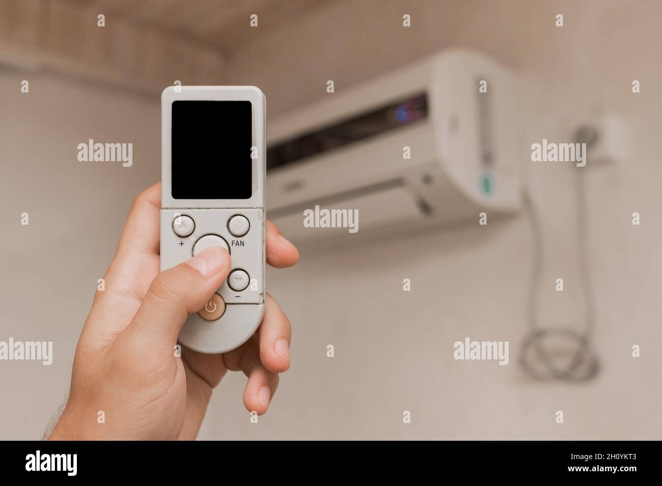 The guy's hand holds the remote control of the air conditioner. Cooling ...