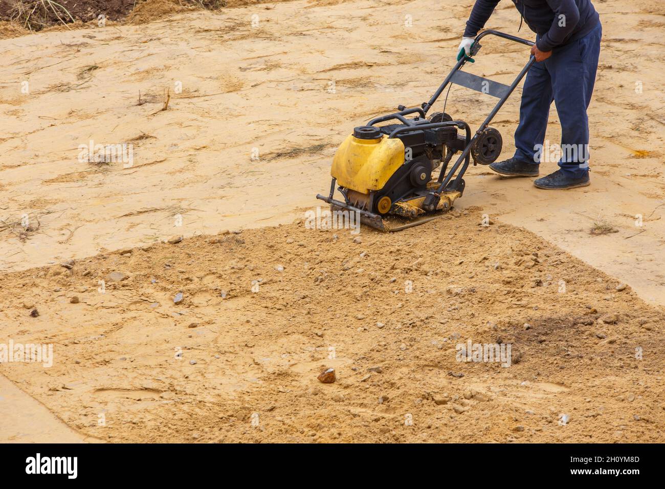 Worker in use vibratory plate compactor for path construction. Plate ...
