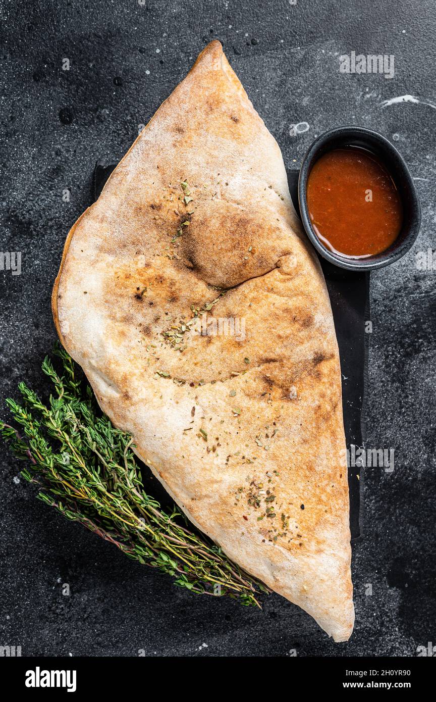 Calzone closed pizza with ham and cheese. Black background. Top view ...