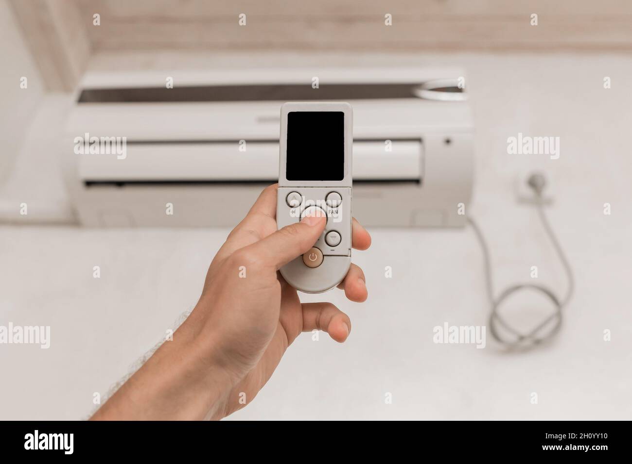 The guy's hand holds the remote control of the air conditioner. Cooling ...