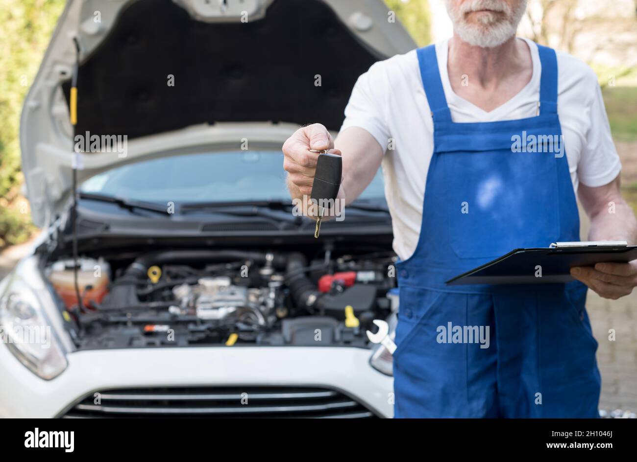 Car mechanic delivering car keys after car engine checking Stock Photo ...
