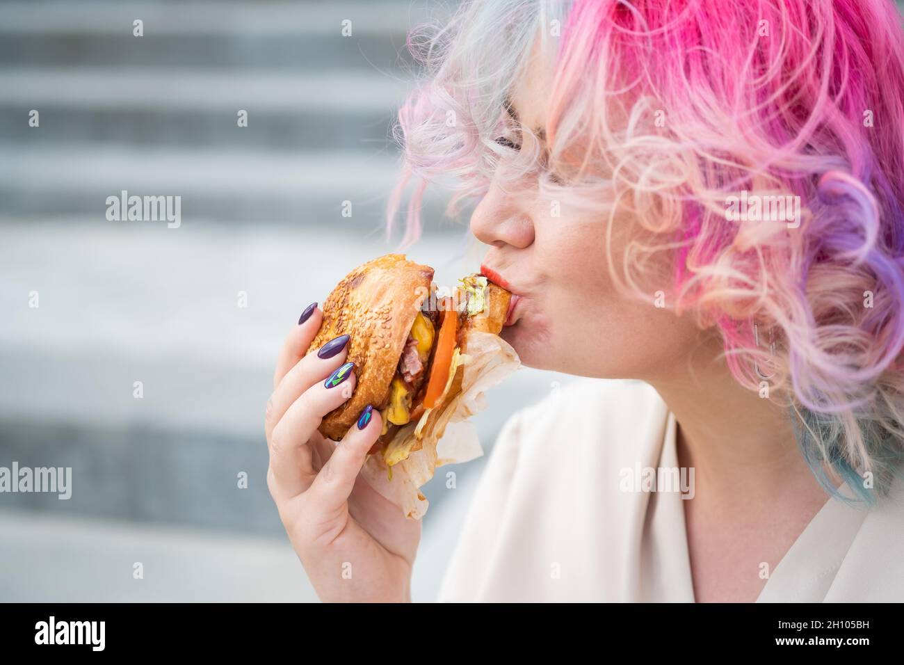Caucasian woman with curly colored hair eating burger. Bad eating ...