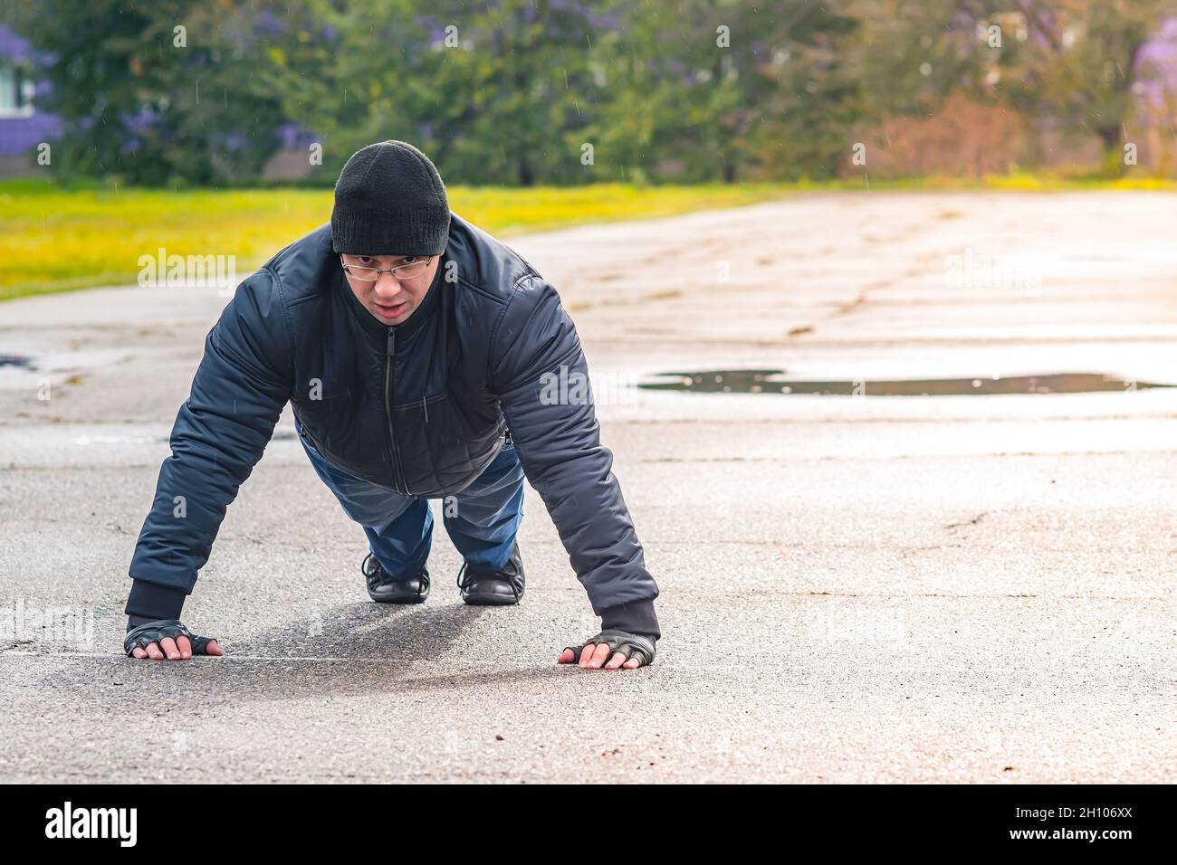 A man performs a classic pectoral exercise outdoors in the rain in the ...