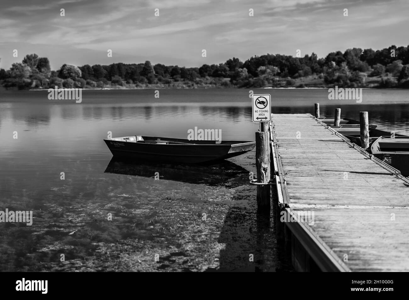 Grayscale shot of an empty boat by a wooden pier of a lake Stock Photo ...