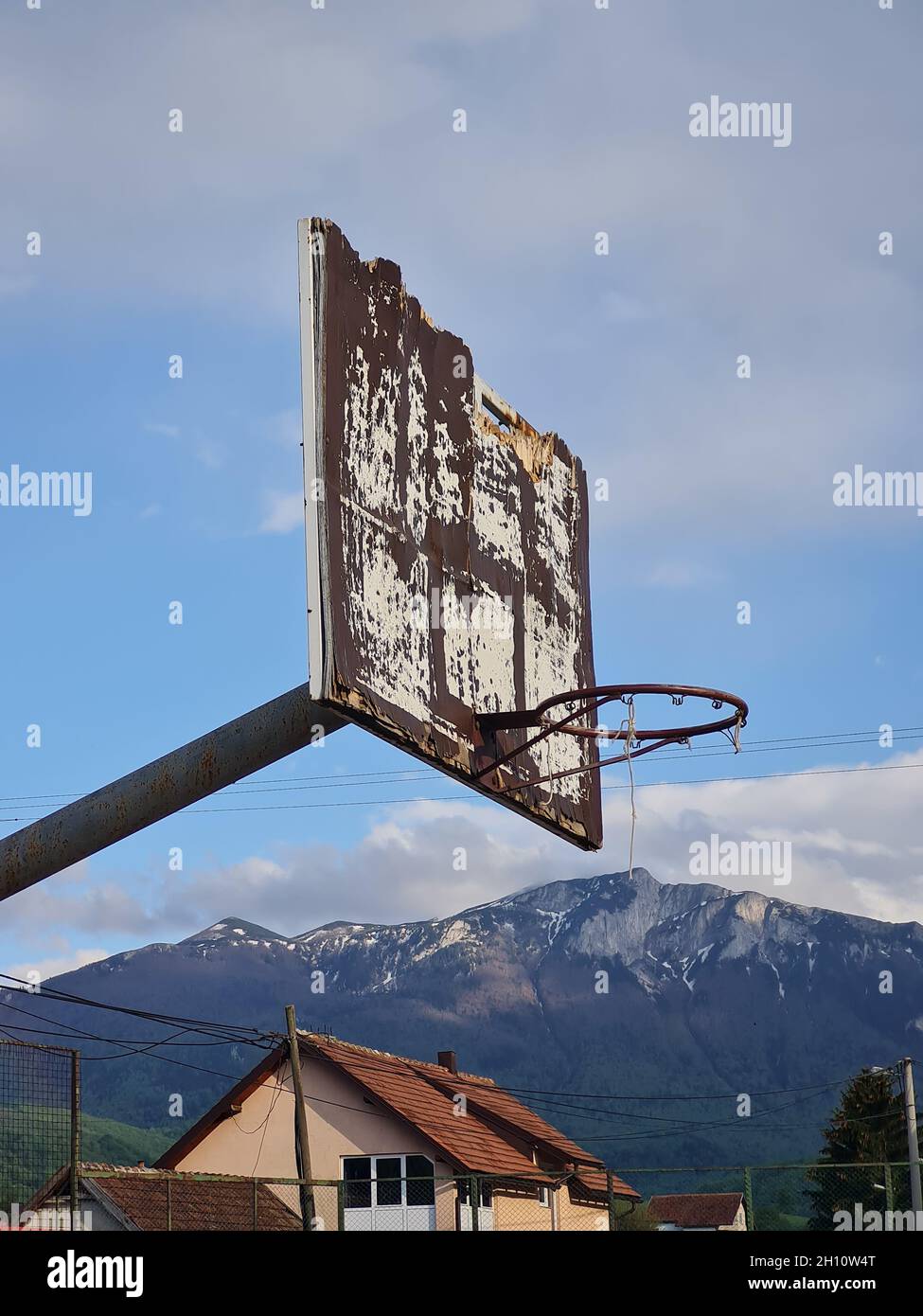 Old and rustic basketball hoop in a village against a mountain ...