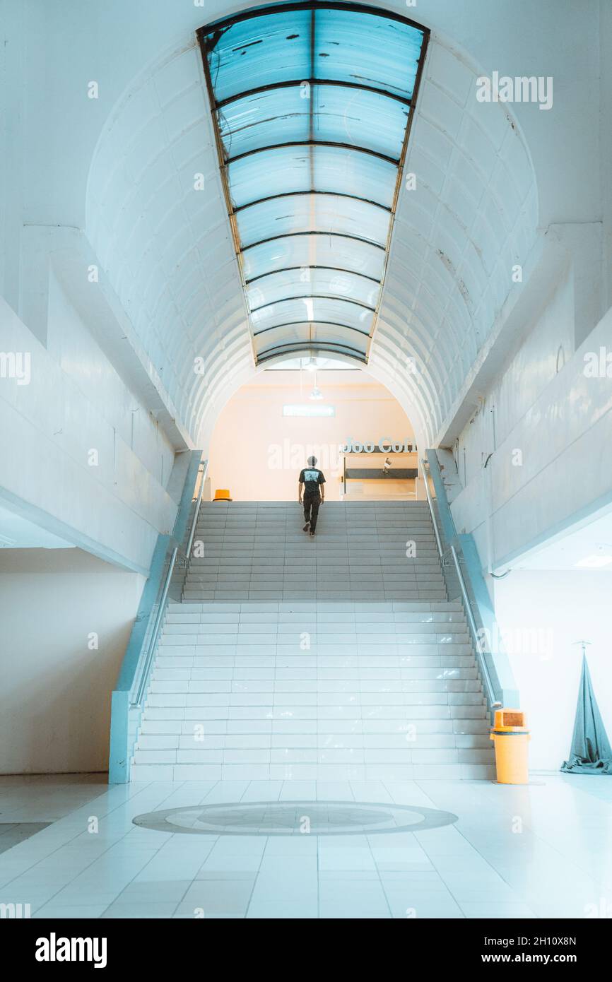 Back view of a man walking up the stairs of the white building alone ...