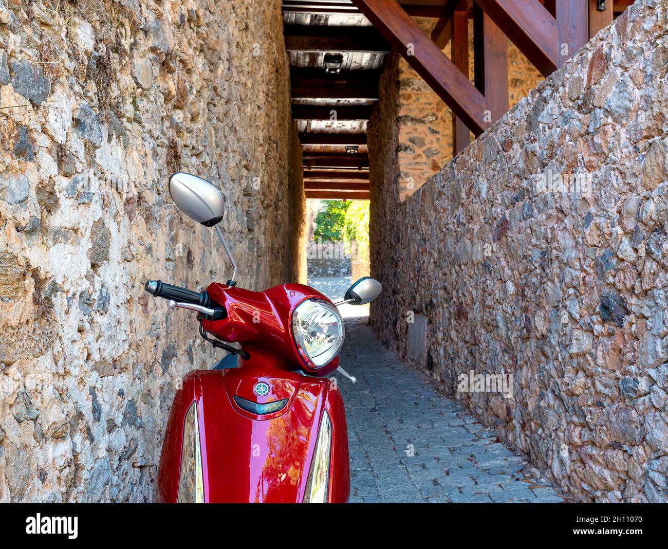 A red moped is parked on a narrow street in the old town area Stock ...