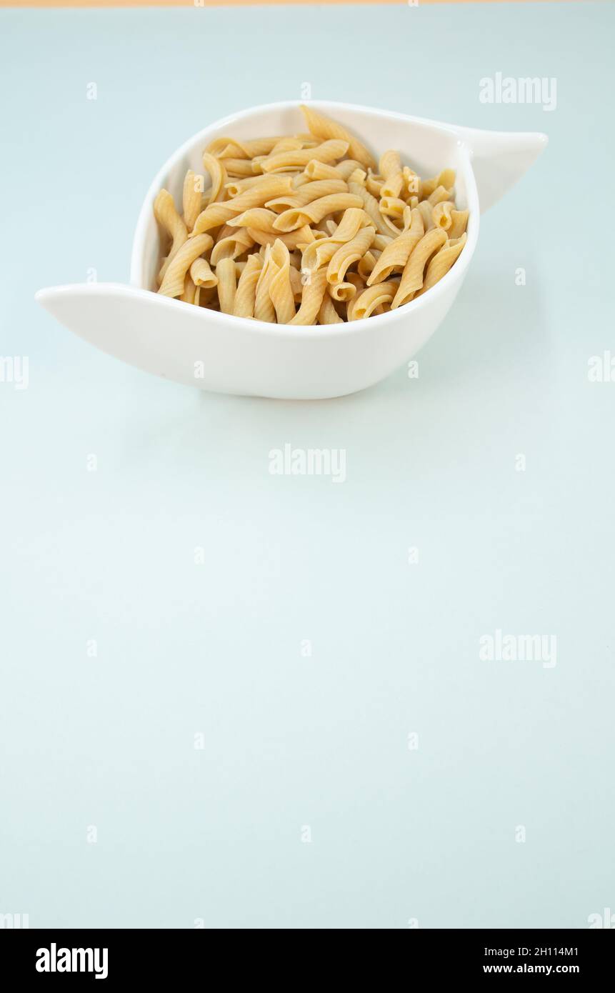 Top view shot of italian pasta in a canister on a light blue surface ...