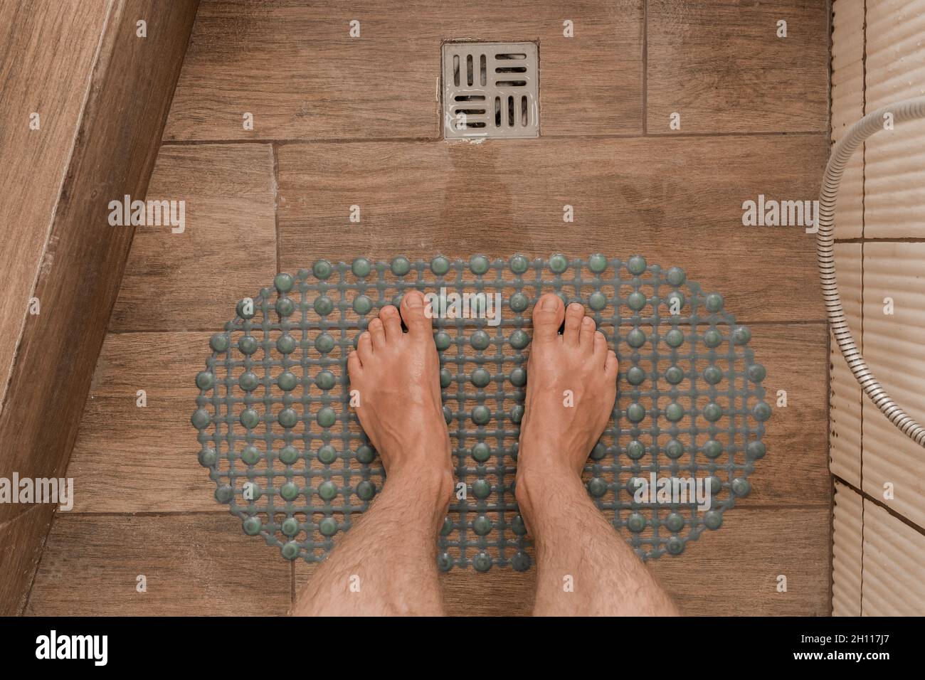 Men's feet stand on a plastic anti-slip mat next to the floor drain in ...