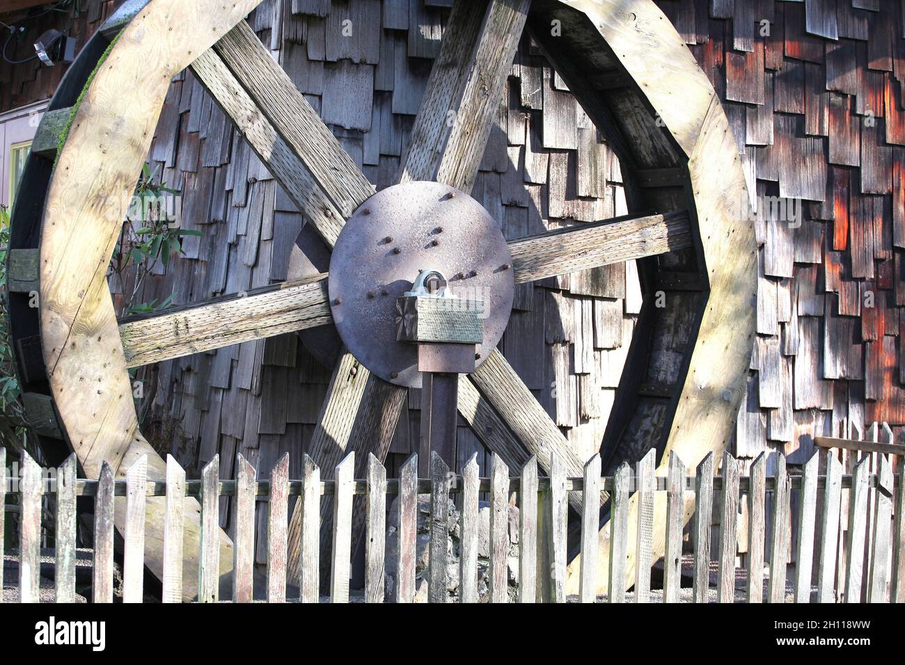 Closeup shot of a big wooden wheel on the wall of a wooden building as ...
