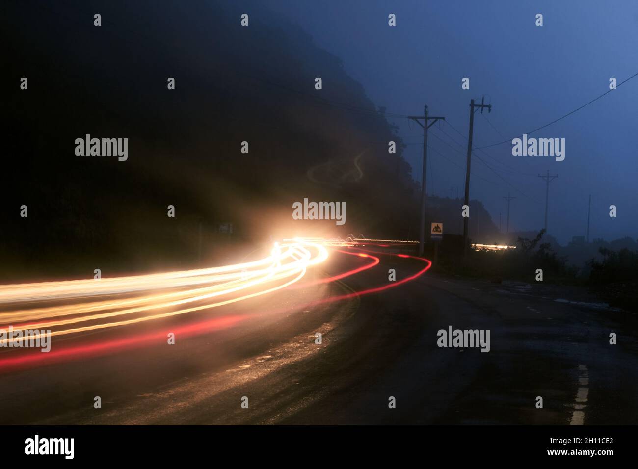 Narrow country lane with abstract bright traffic light trails at night ...