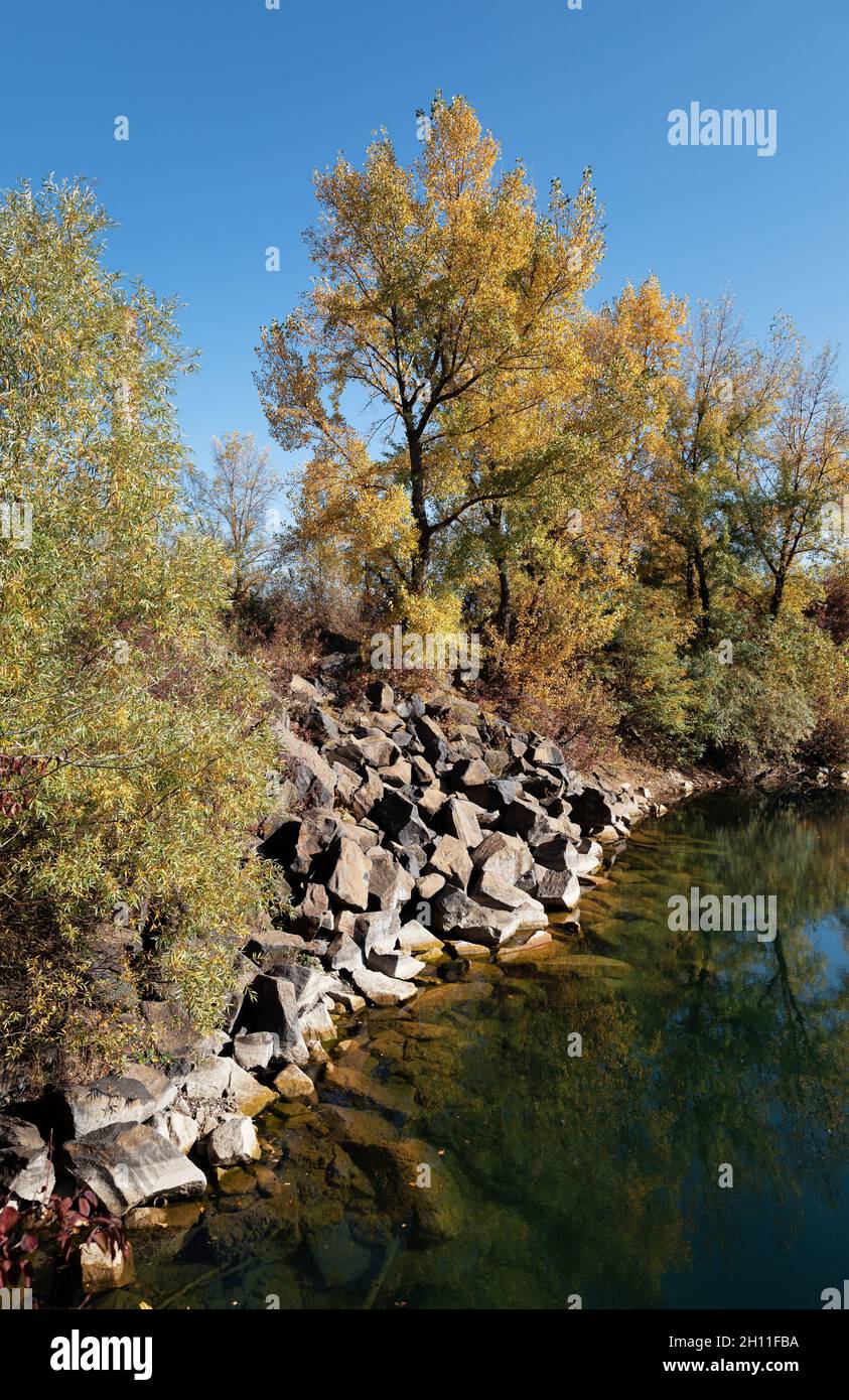 Golden autumn with colourful trees in old flooded quarry. Rocks, lake ...
