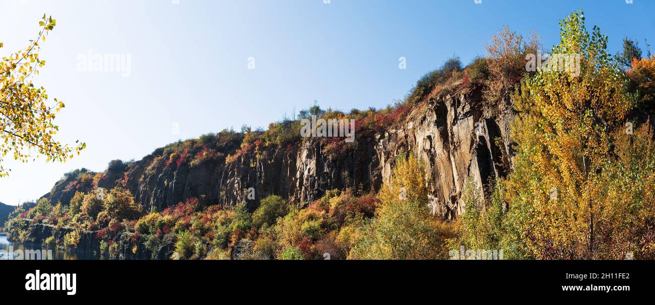 Golden autumn with colourful trees in old flooded quarry. Rocks, lake ...